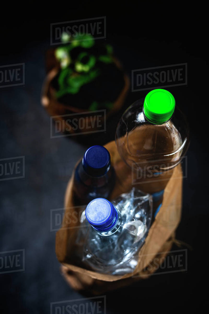 from above dirty paper sack with discarded plastic bottles placed on ...