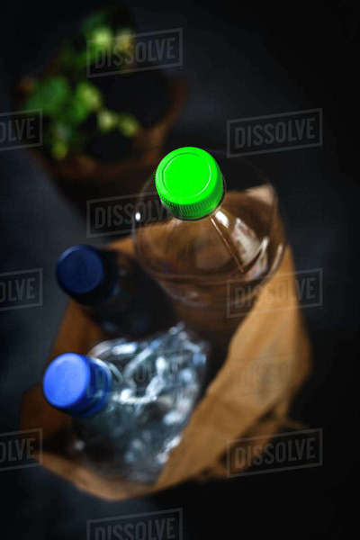 from above dirty paper sack with discarded plastic bottles placed on ...