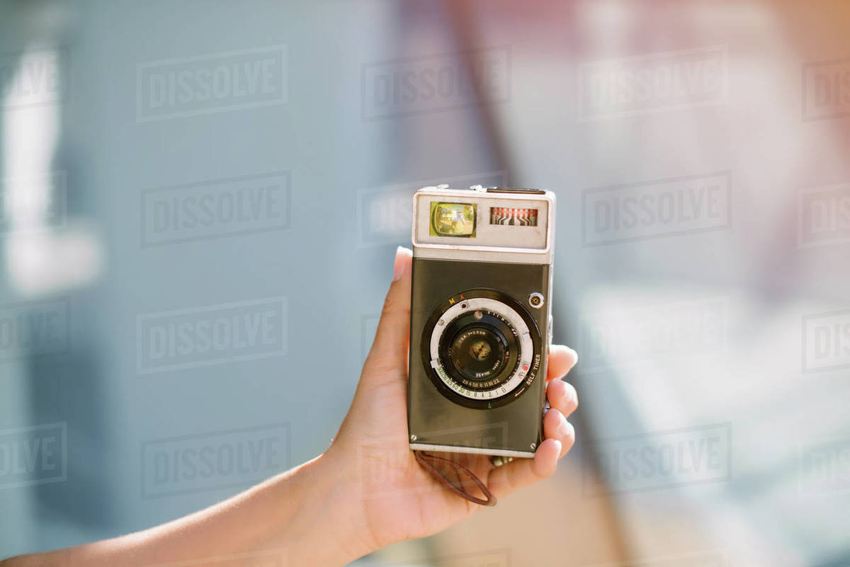 Crop hand of young woman holding portable analog photo camera against ...