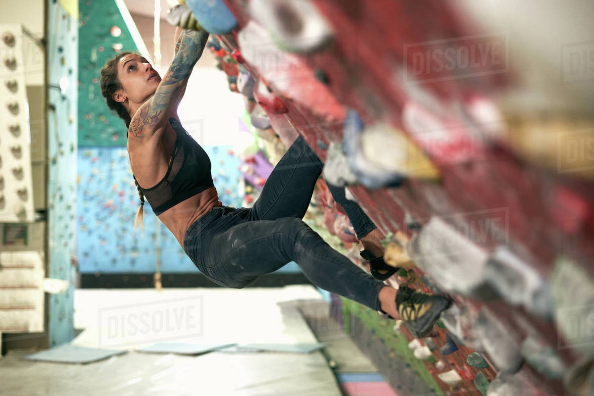From below side view of woman athlete tattooed powerful woman climbing ...