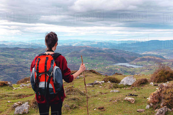 Back view of unrecognizable hiker with backpack and stick standing with ...