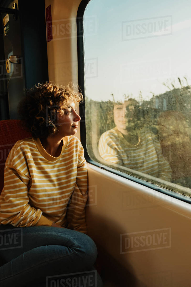 Young woman looking out train window - Stock Photo - Dissolve