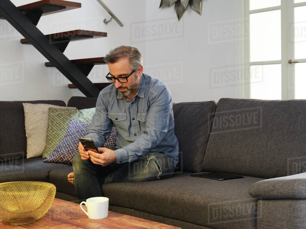 Man using phone alone on sofa in living room at home - Stock Photo ...