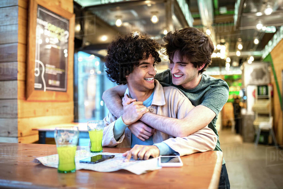 Multiethnic young homosexual men embracing each other looking at ...
