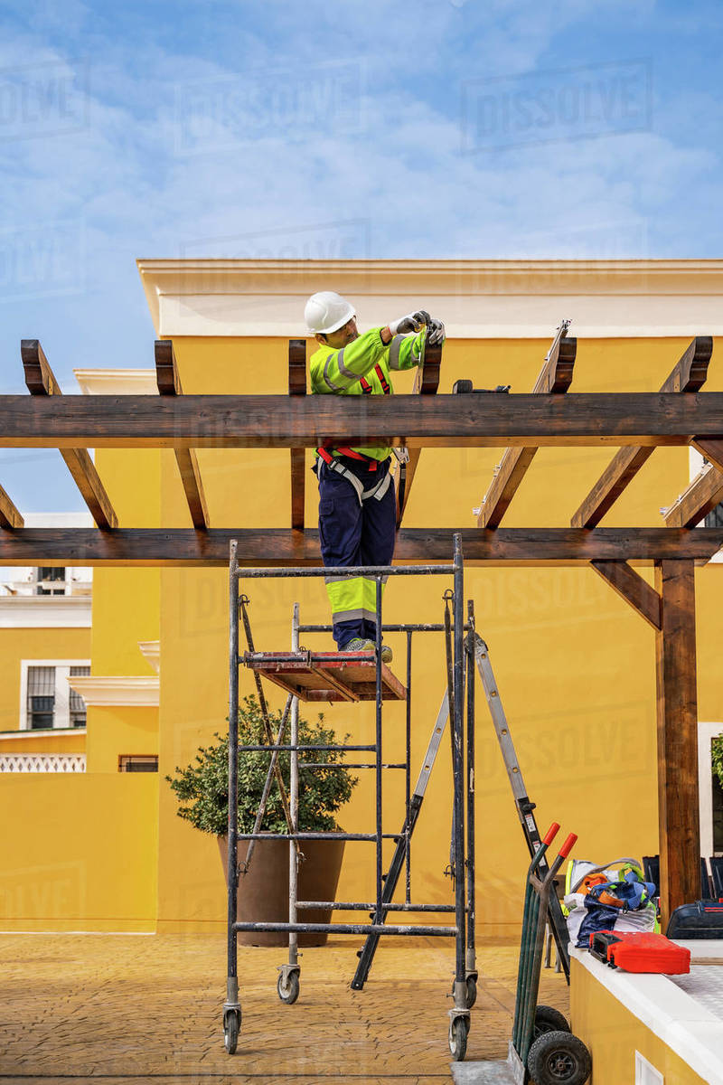 From below side view of male technician in work wear standing on ...