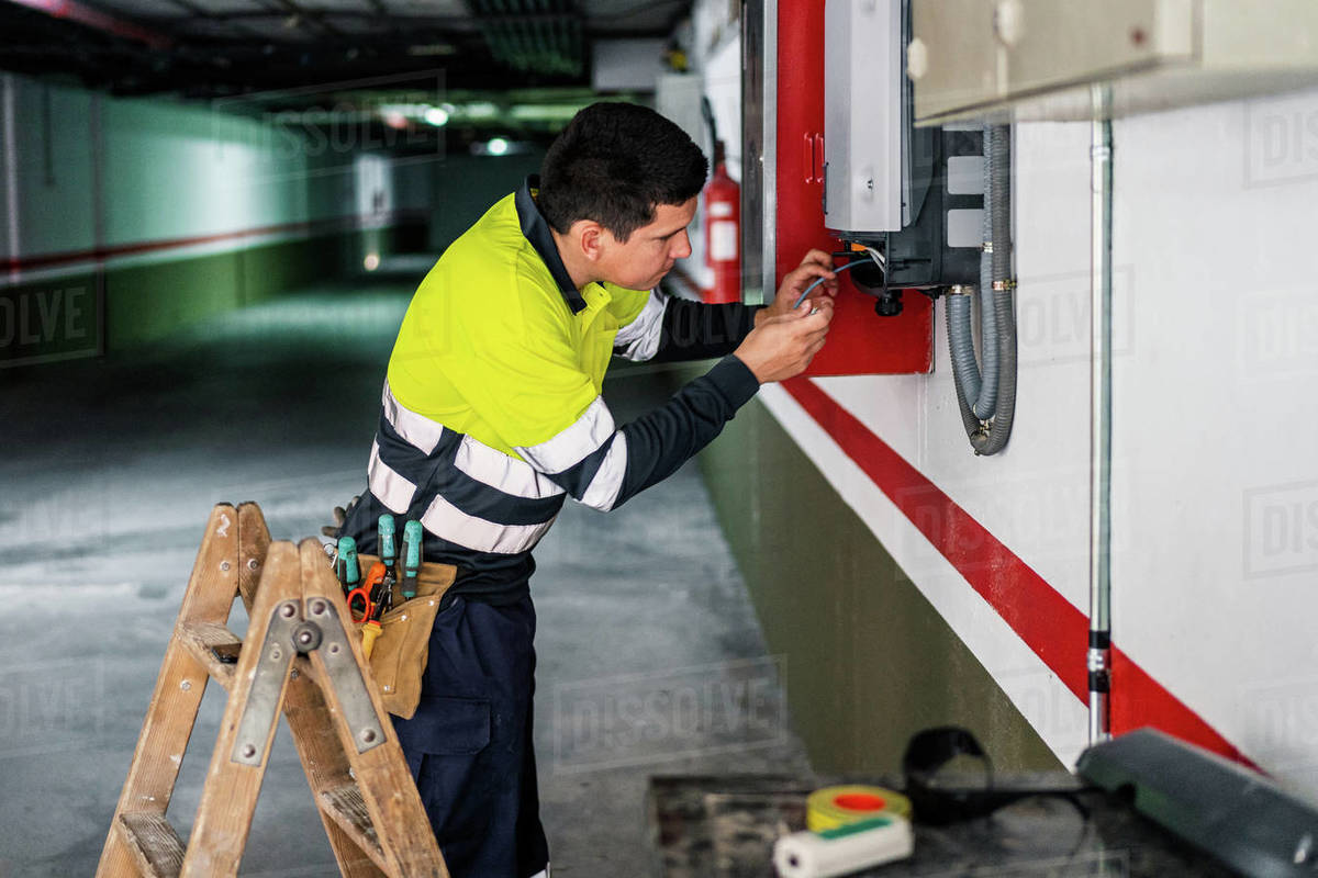 Side view of young professional male technician with electric tools ...
