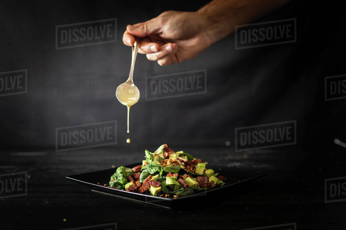 Unrecognizable cook adding spoonful of sauce into a yummy portion of ...