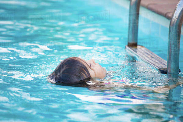 Cute girl floating on back in clean water and looking up while spending ...