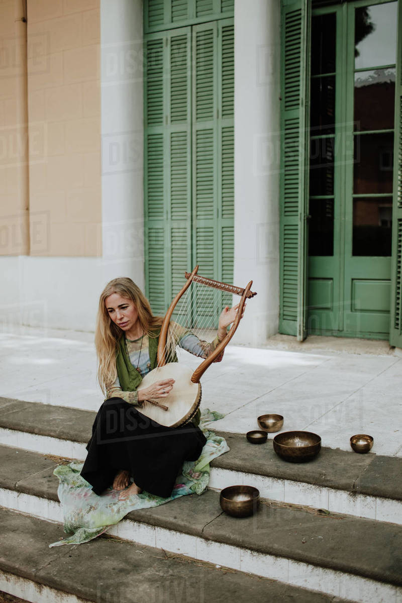Female playing lyre on steps - Stock Photo - Dissolve