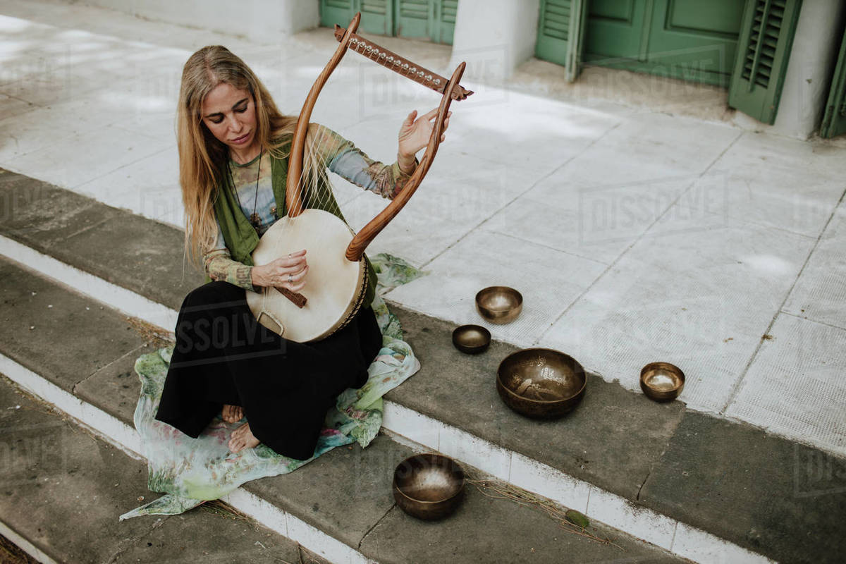 Female playing lyre on steps - Royalty-free Stock Photo | Dissolve