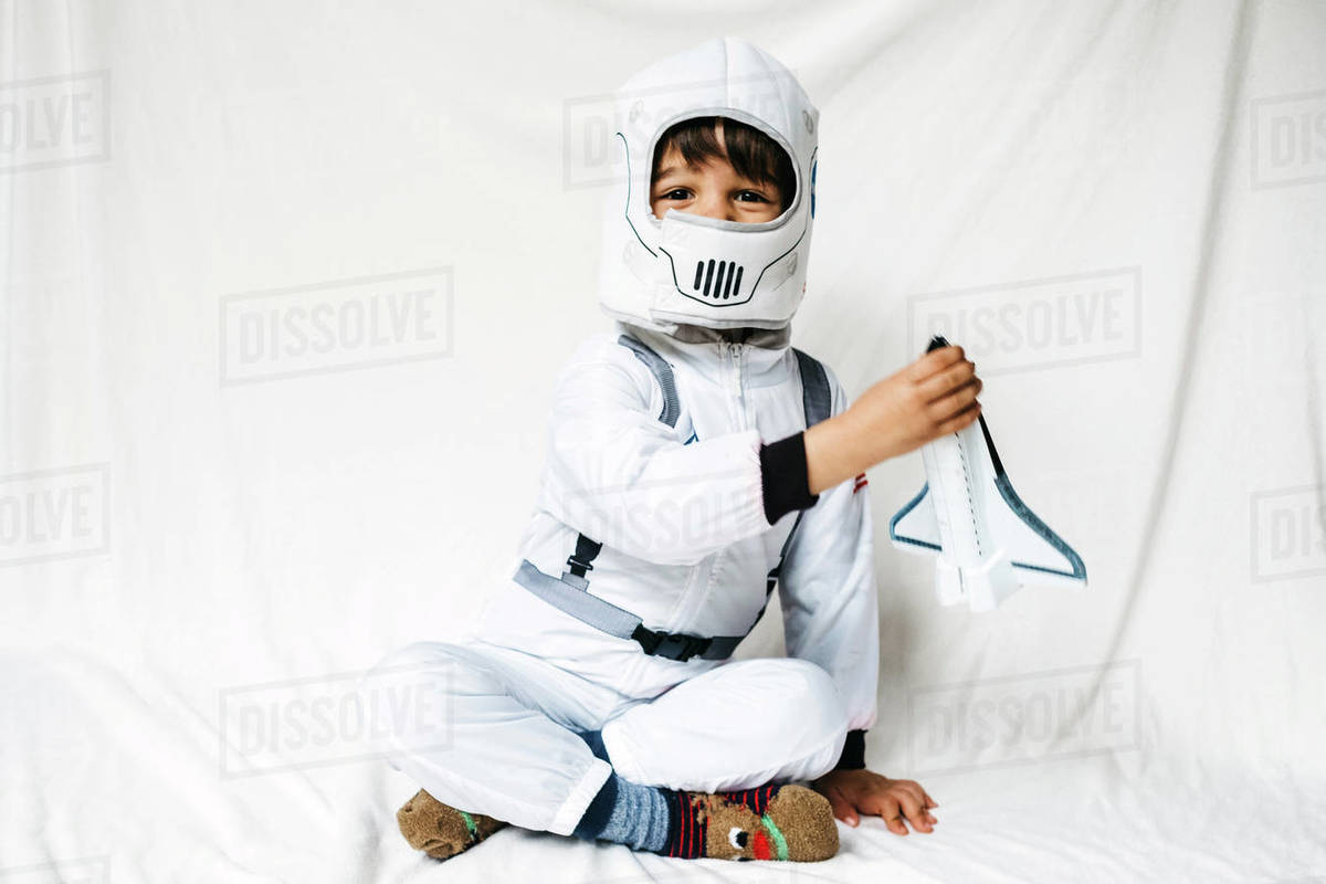 Delighted kid wearing astronaut suit and helmet looking at camera ...