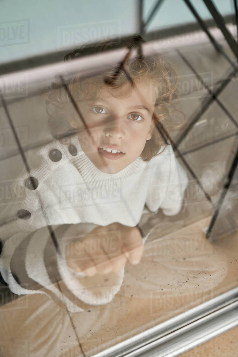 Happy boy standing behind window - Stock Photo - Dissolve