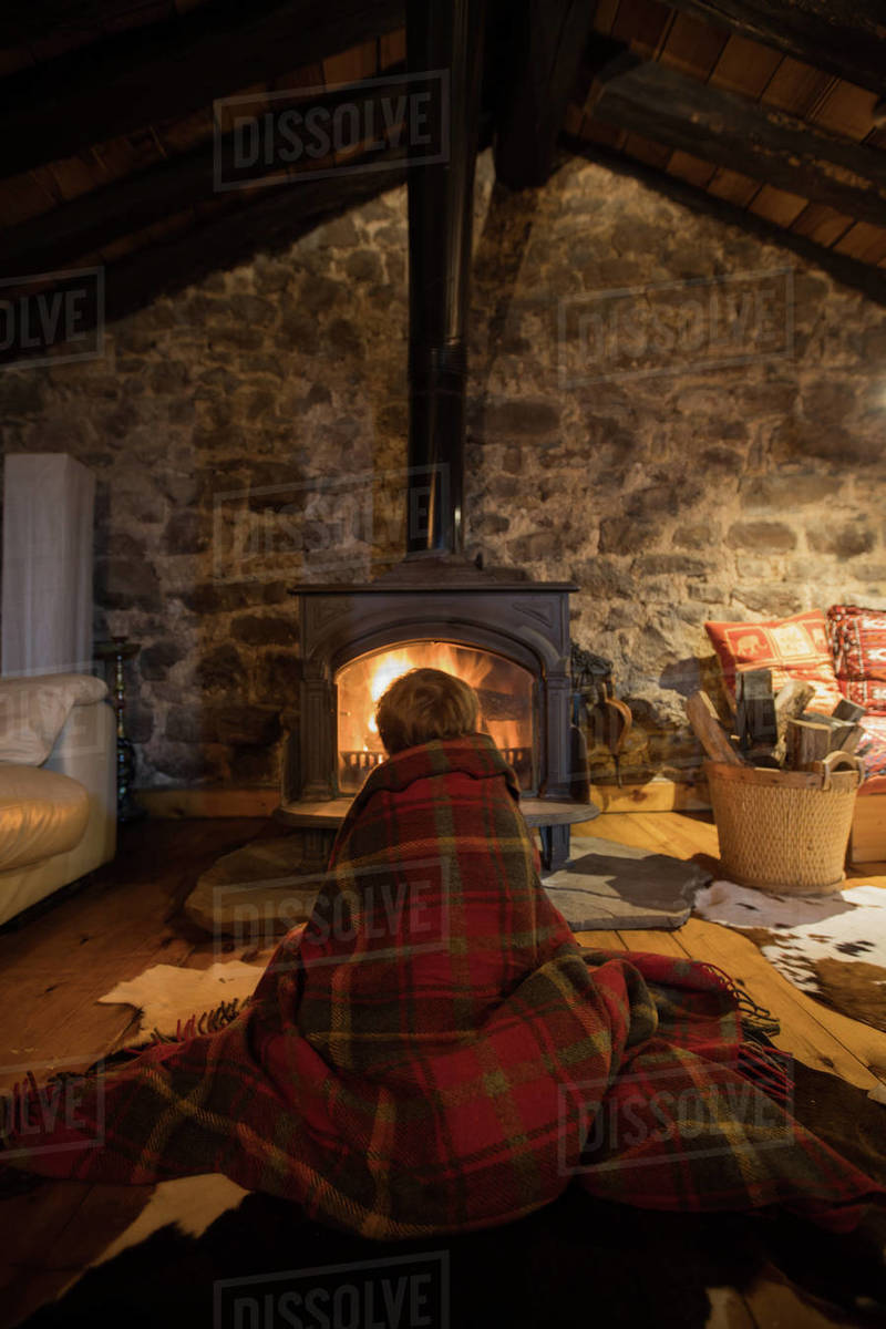 Cuddling kid wrapped in cozy tartan plaid sitting on wooden floor near ...