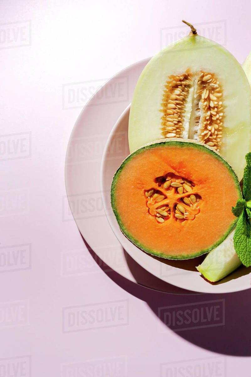 Fresh assortment melon with mint on pink background with high contrast ...