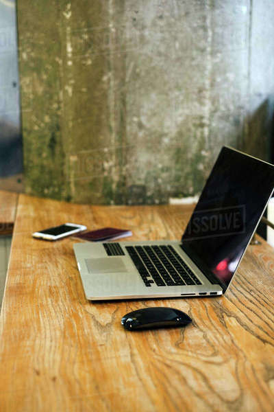 Modern netbook placed on wooden table with smartphone and mouse in cozy ...