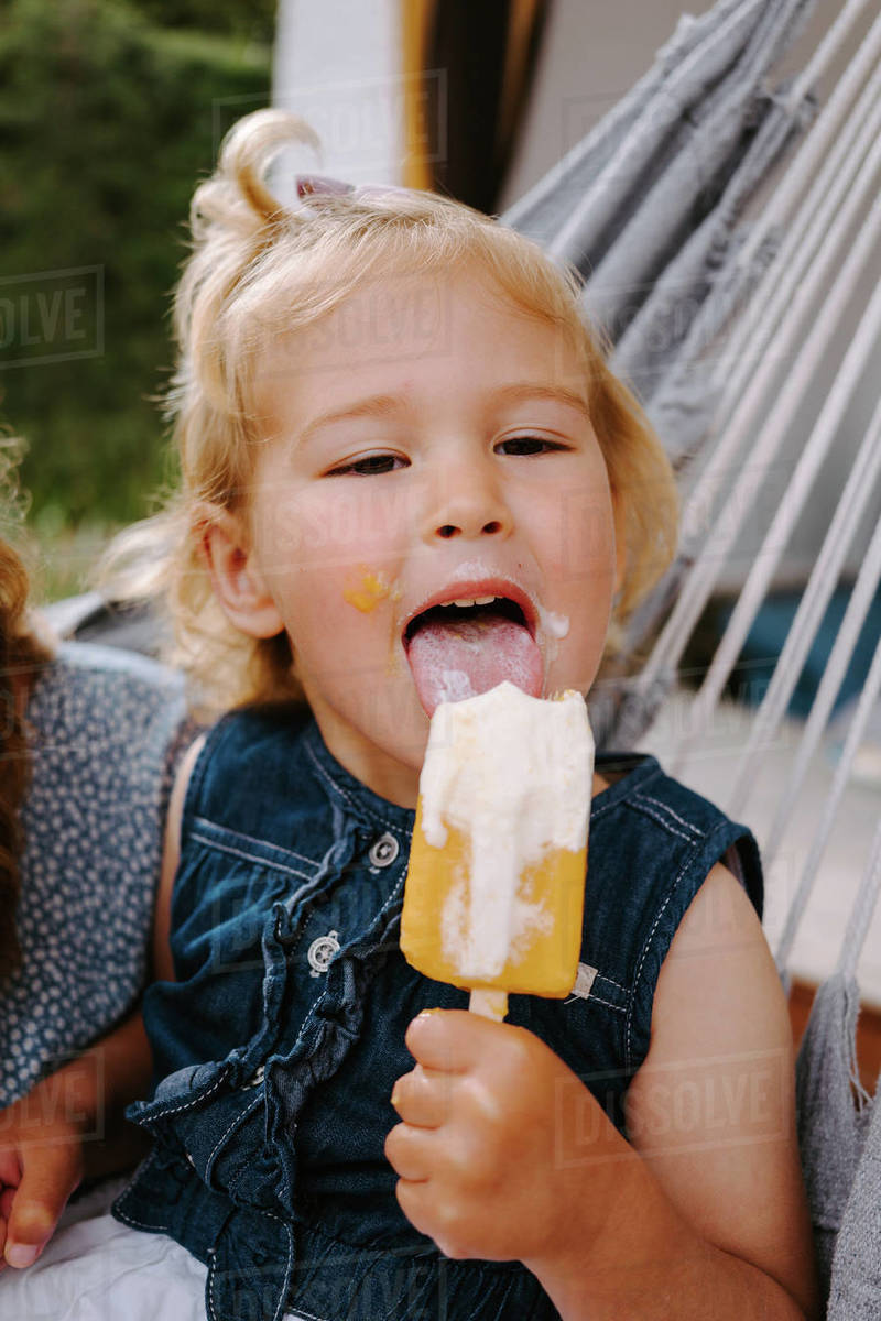 Content little kid eating homemade popsicle on stick while relaxing on ...