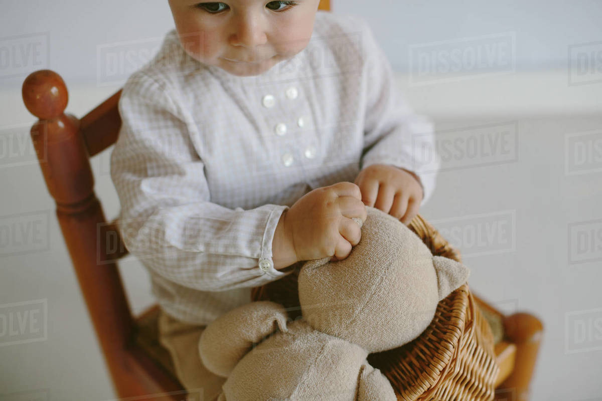 From above of crop little child sitting on wooden chair in living room ...