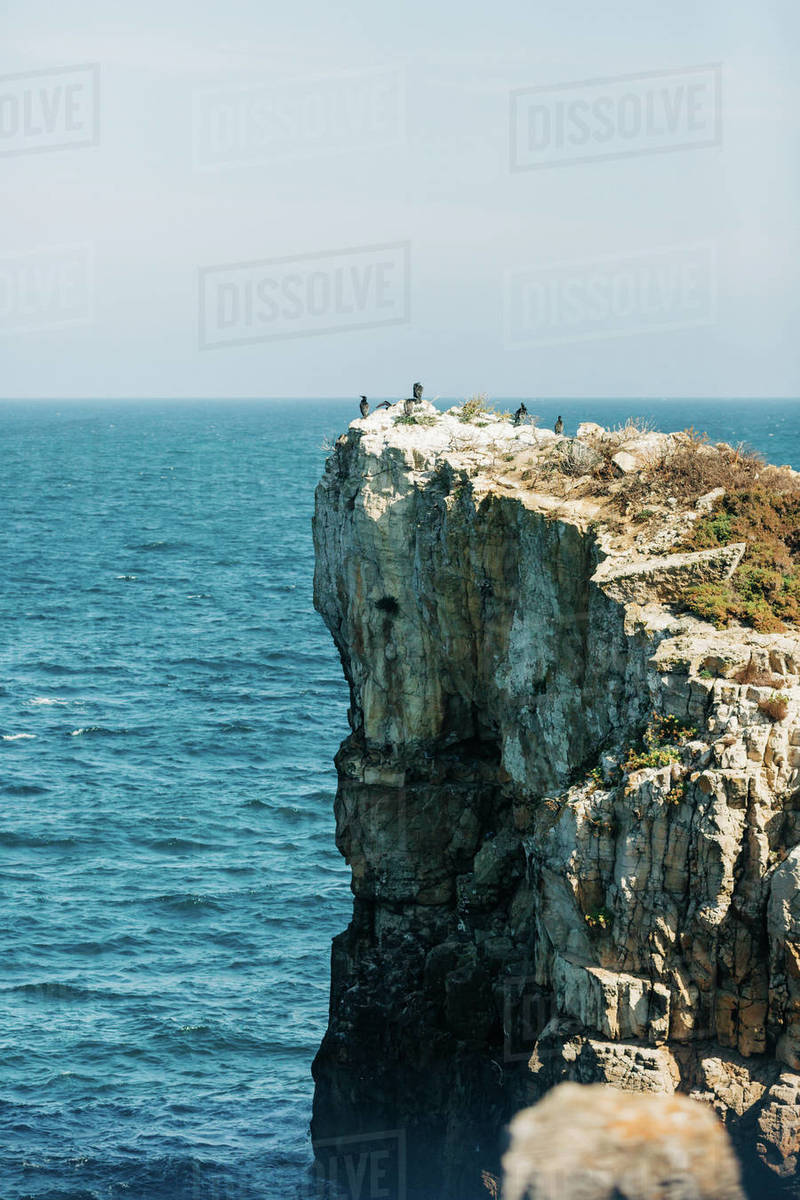 Rough cliff in blue sea - Royalty-free Stock Photo | Dissolve