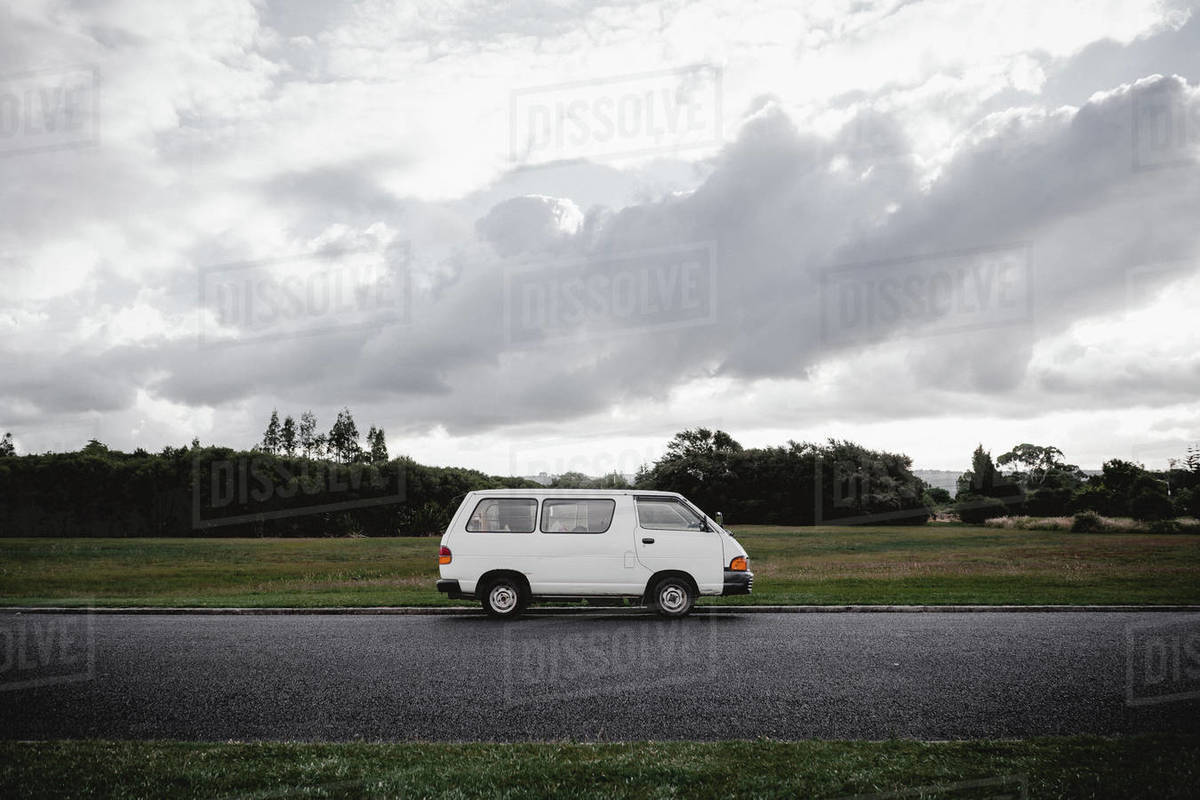 White van riding on asphalt countryside road on majestic cloudy day in ...