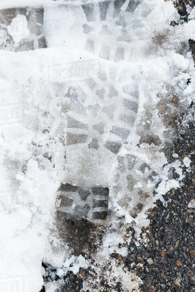 Top view close up of new shoe prints on thin layer wet clean fresh snow ...