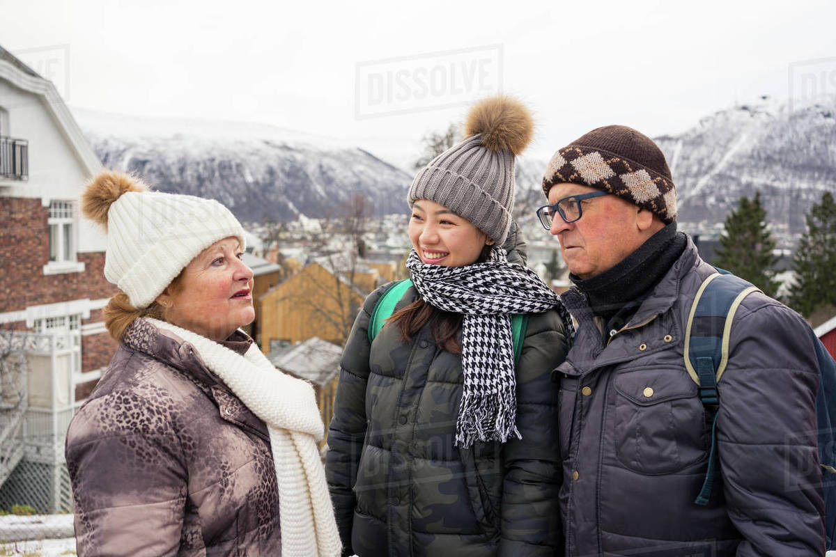Pleased Asian female on vacation in warm clothing laughing while ...