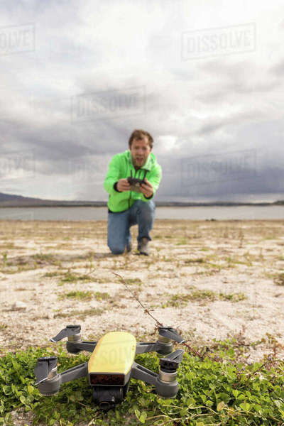 Immersed keen man lifting drone with camera from land using remote ...