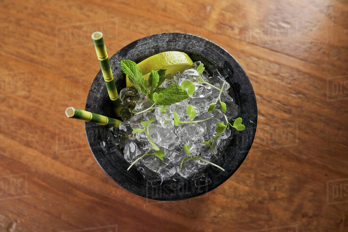 Fresh cold ready beverage with ice and straw in modern ceramic cup on ...