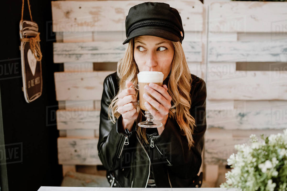 Long haired trendy woman holding glass of delicious foamy coffee ...