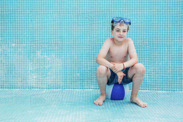 Boy sitting on ball in empty pool - Royalty-free Stock Photo | Dissolve
