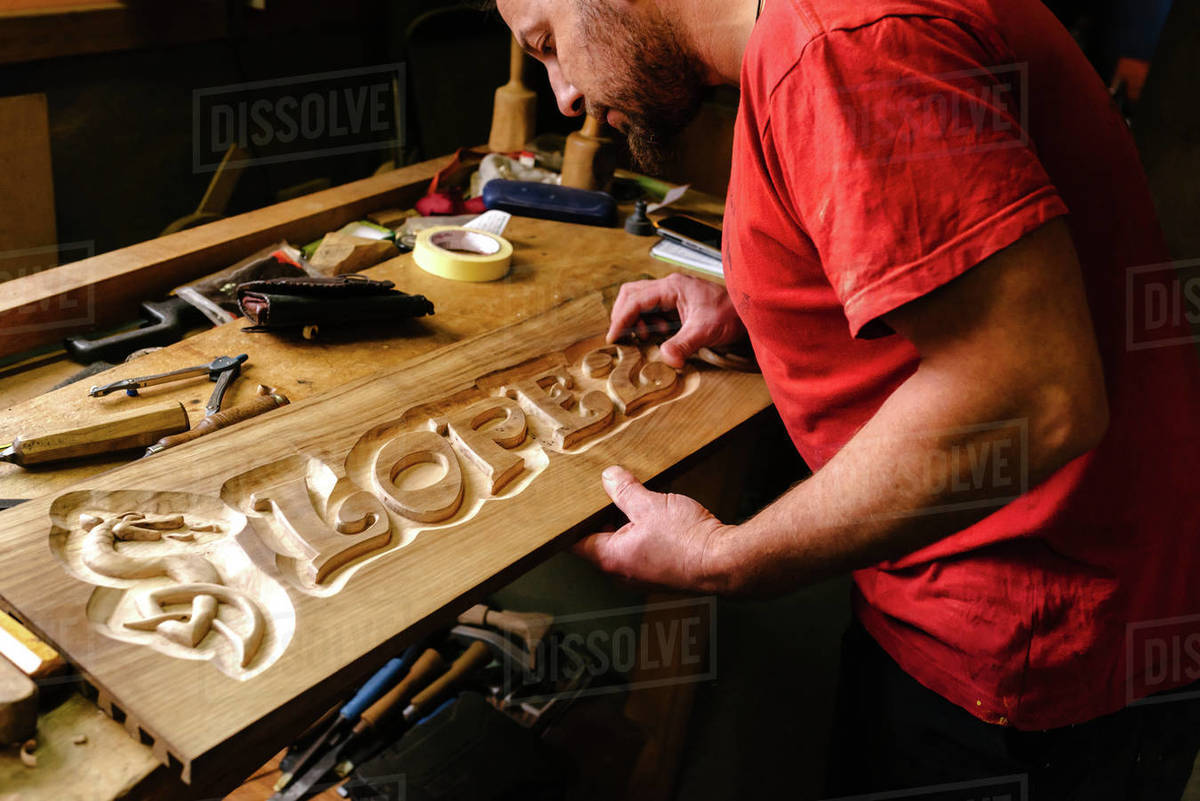 Side view of talented male woodworker standing at table with wooden ...