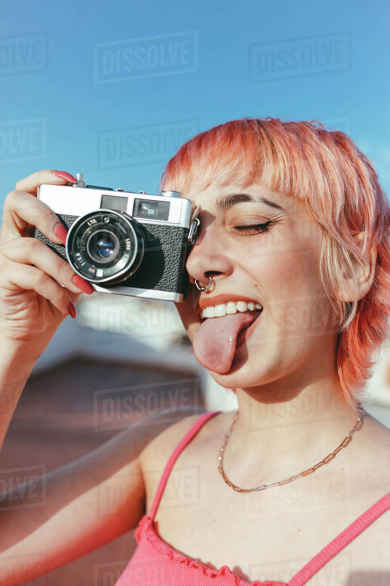 Naughty female millennial with piercing and pink hair taking pictures ...