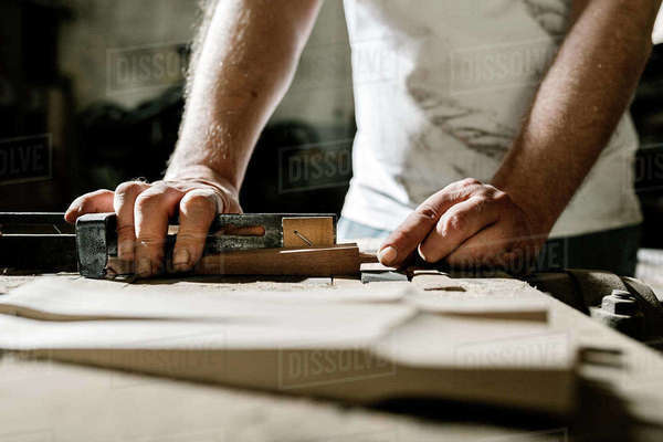 Crop male woodworker standing at old workbench and working with lumber ...