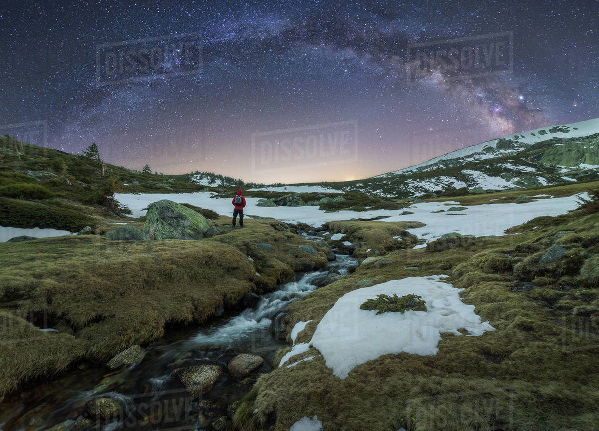 Back view of unrecognizable distant hiker standing near small river ...