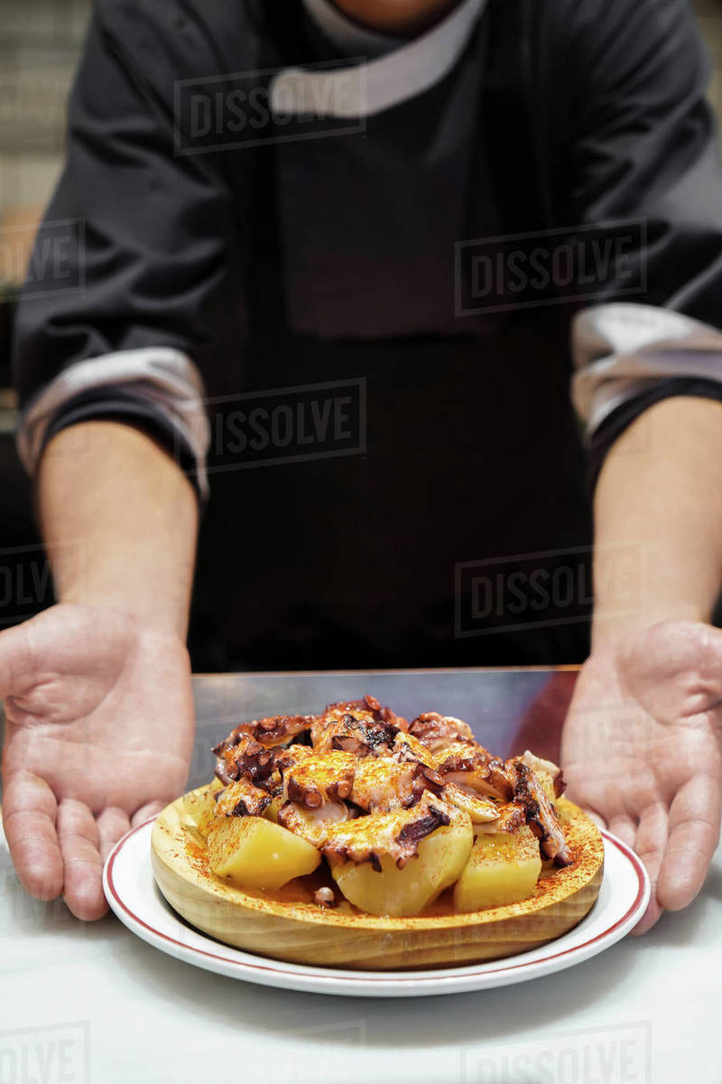 Faceless person in black restaurant uniform giving plate with boiled ...