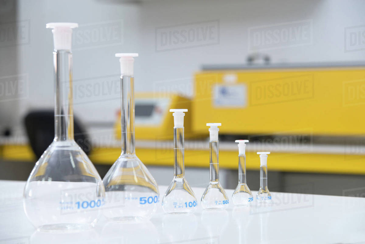 Various glass flasks placed in row on table and prepared for ...