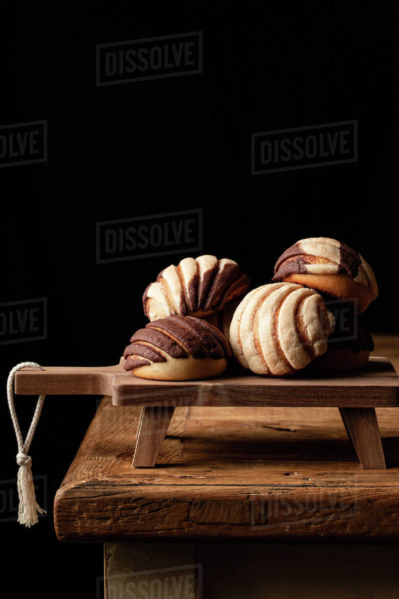 Freshly baked traditional concha bread placed on wooden cutting board ...
