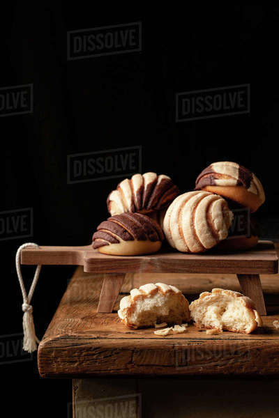 Freshly baked traditional concha bread placed on wooden cutting board ...