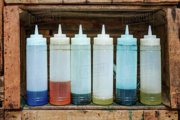 Set of transparent plastic containers with assorted multicolored liquid ...