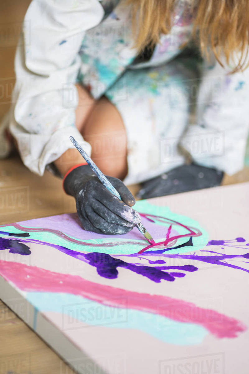 Crop anonymous female illustrator in dirty robe and gloves sitting on ...