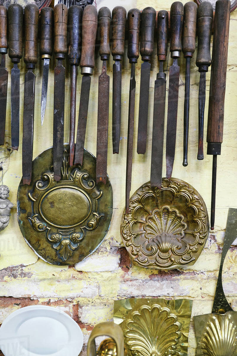 Collection of used sharp files with rounded handles hanging on brick ...