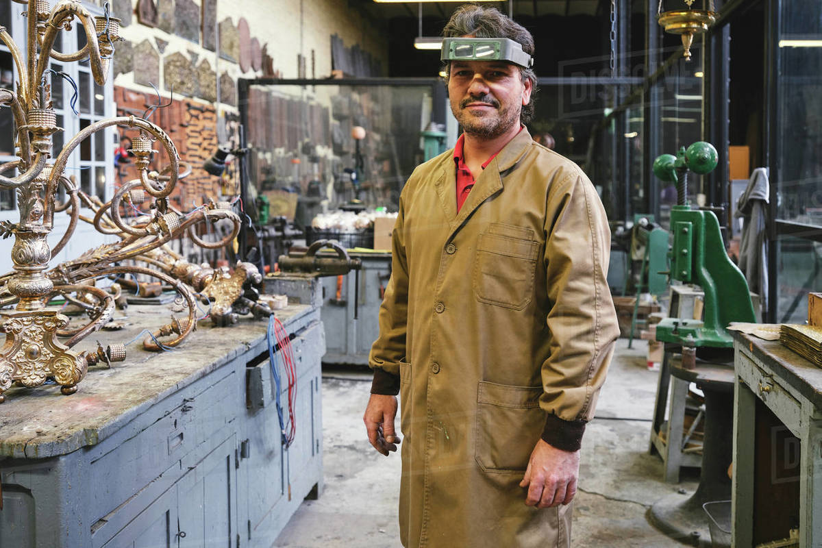 Positive mature goldsmith in robe and head magnifying glasses standing ...