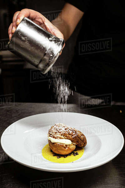 Unrecognizable chef spilling sweet powdered sugar of plate with yummy ...