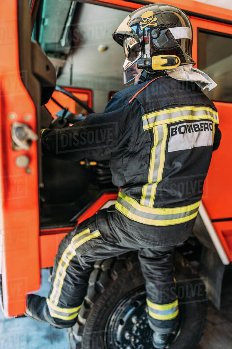 Back view of faceless firefighter in warm uniform and protective cap ...