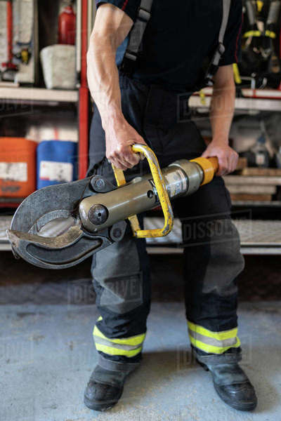 Crop unrecognizable fit firefighter in uniform and footwear holding ...