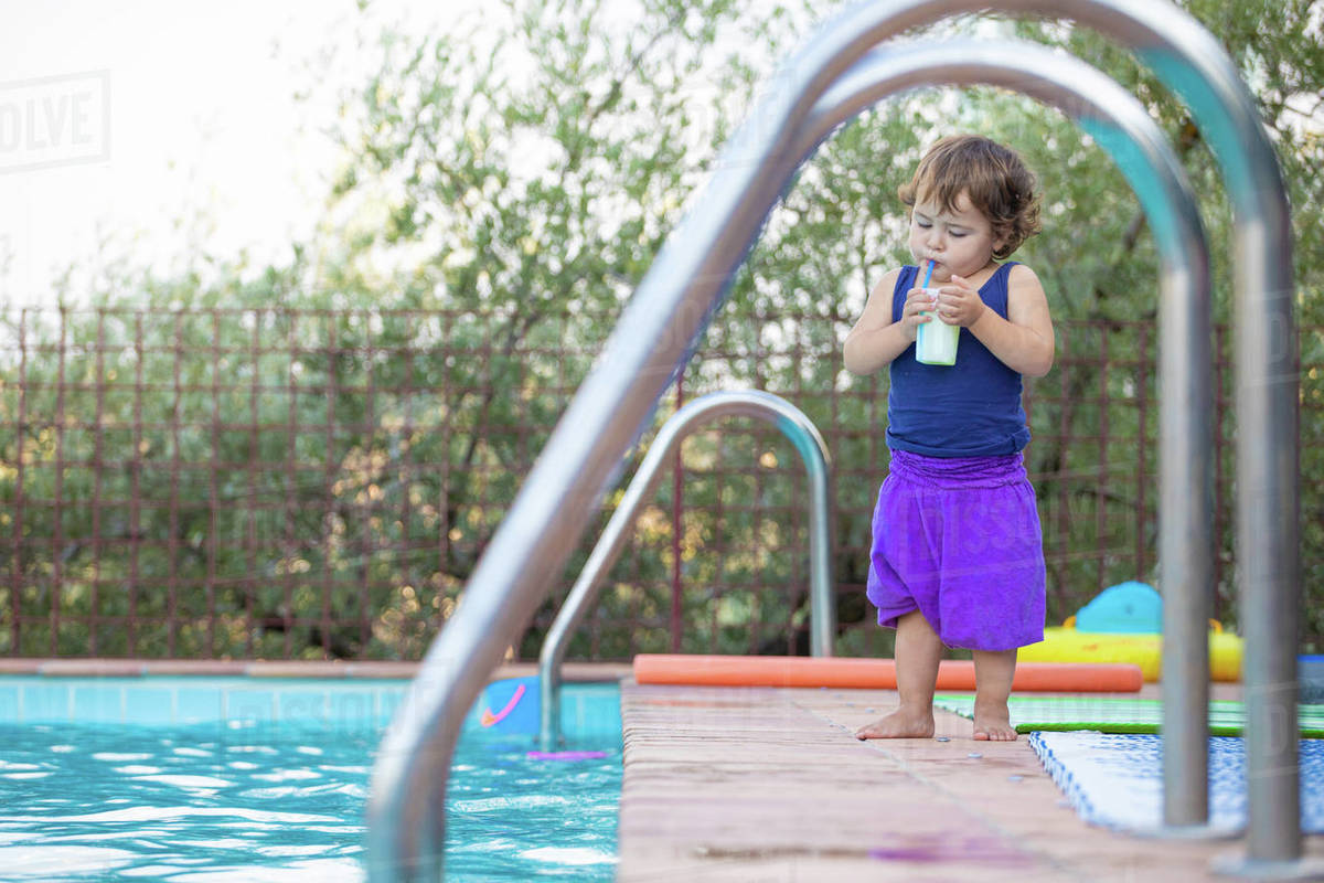 Cute little child sipping fresh beverage through straw and looking away ...