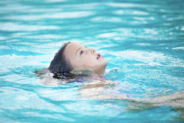 Cute girl floating on back in clean water and looking up while spending ...