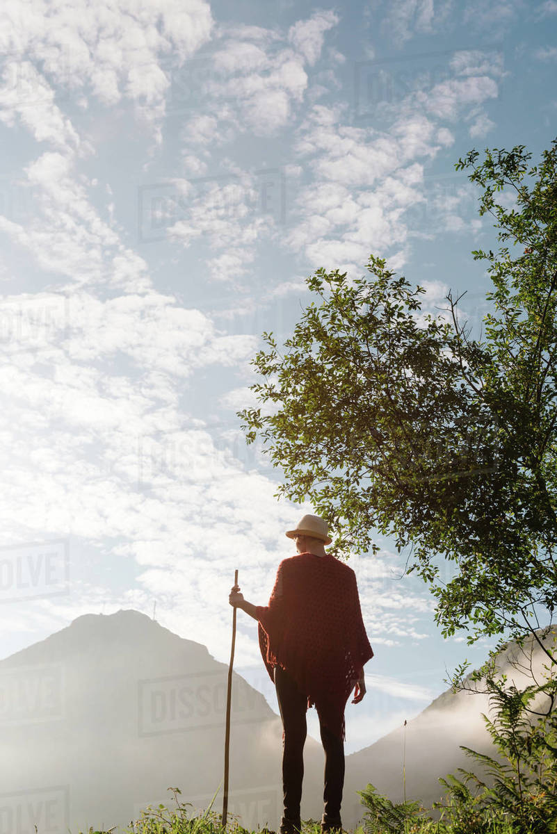 Back view of unrecognizable wanderer with wooden staff enjoying sunrise ...