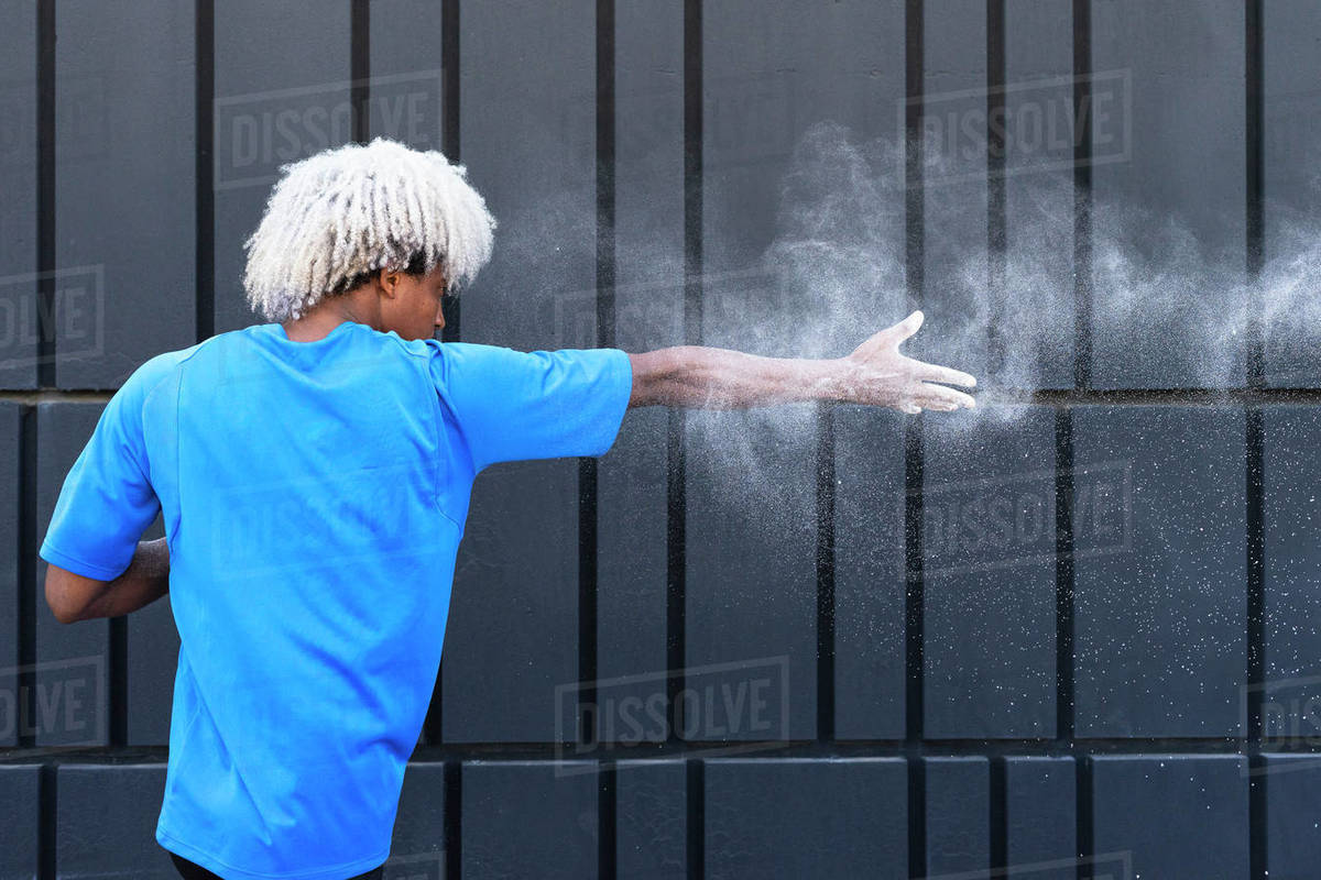 Back view of black sportsman with dyed hair throwing chalk powder in ...