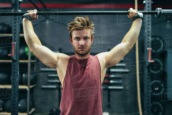 Strong male athlete doing exercises with barbell while working out in ...