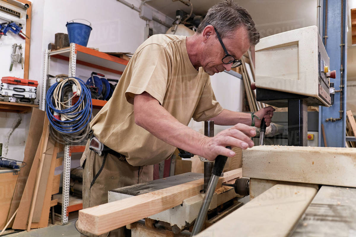 Low angle of attentive middle aged male woodworker in glasses and ...